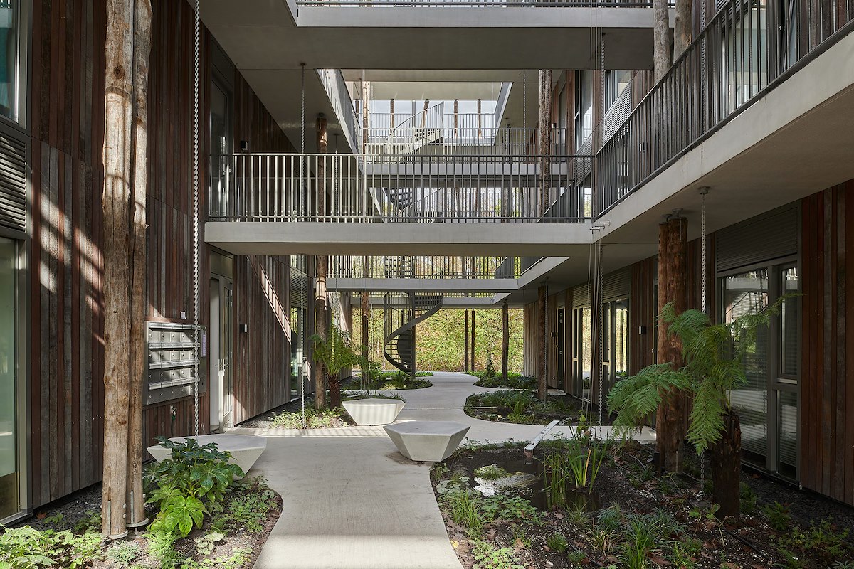 Colonnades van boomstammen en groene doorgang kenmerken woongebouw ...